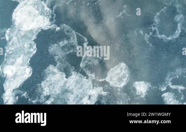 An aerial view from above on the frozen reservoir. Cracks and shards of ...