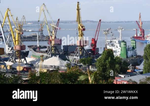 Bulker ship under load of clinker cargo loading by shore cranes with ...
