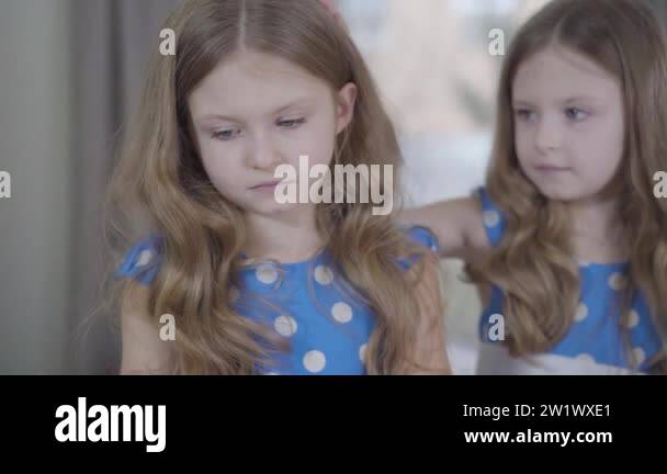 Close-up portrait of upset Caucasian little girl yelling at twin sister ...