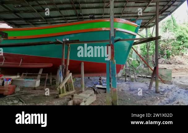 Pan left view of a traditional wooden boat under construction from bow ...