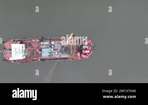 A barge loaded with scrap metal and waste floating on a water surface ...
