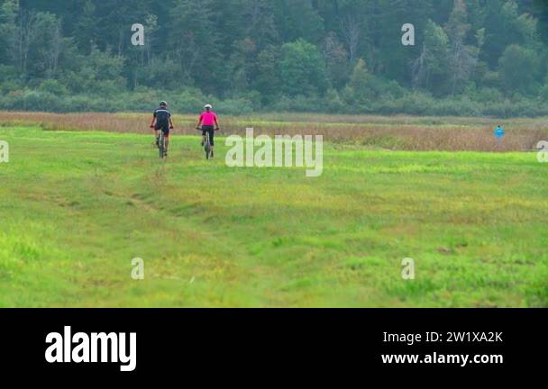 A couple is enjoying a bike ride out in the green nature. It looks ...
