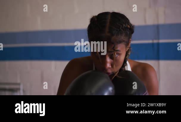 Portrait close up of a mixed race female boxer with long, dark plaited ...