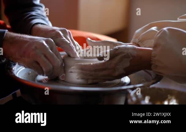 A lesson of ceramics. Hands of the teacher and student on a rotating ...