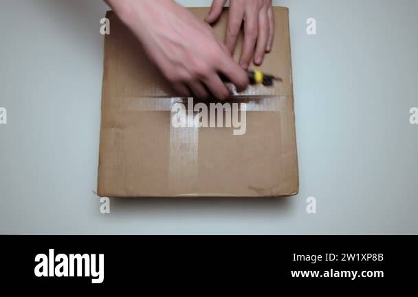 Unpacking the parcel. A man cuts the packaging with a knife. Male hand ...