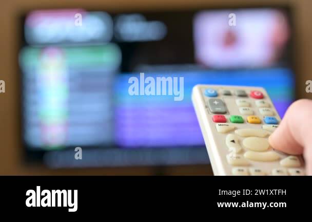 Watch TV. Closeup male hand switches television channels, on the background of the television ...