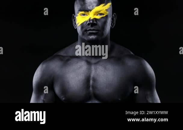Man bodybuilder athlete with yellow color on face art and black body ...
