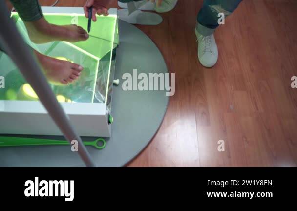 Barefoot female patient staying on transparent glass surface with green ...