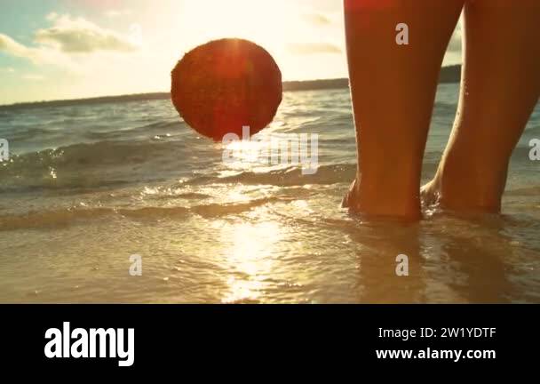 coconut falling into the white sand beach with human legs being washed ...