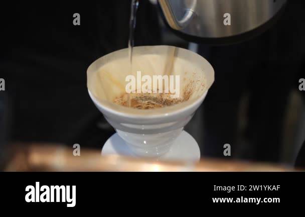 Barista pours water from a pot into a filter with coffee, brewing ...