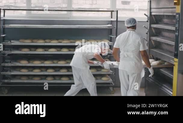 Process of load the raw bread in the oven machine of two bakery workers ...