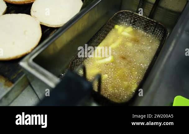 French fries cooking in deep fryer in hot oil.Golden potato chips being ...