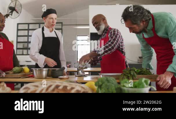 group of senior adults at a cookery class in a restaurant kitchen, the ...