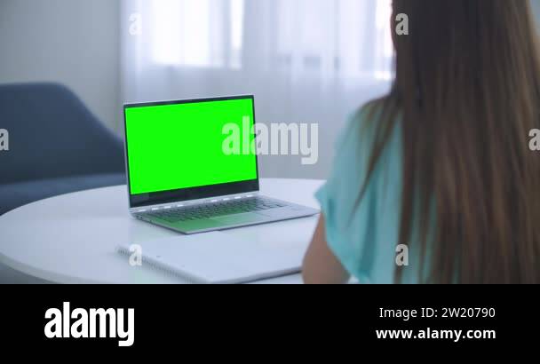 Girl taking notes in notepad from laptop computer Green Mockup Screen ...