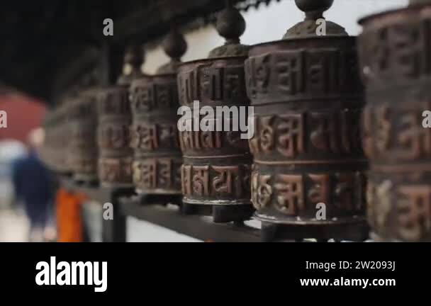 A close view of spinning buddhist prayer wheels in a row of wheels in ...