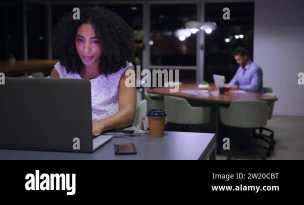 Front view of a focused mixed race businesswoman working late in a ...