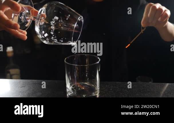 Cooking cocktail with fire on bar counter at night club. Close-up of ...