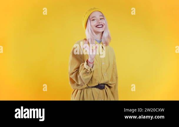 Positive girl making OK sign over yellow background and smiles to ...