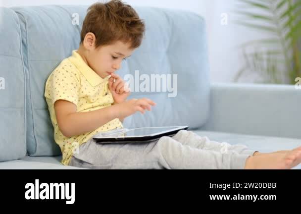 Preschool boy using tablet computer for online education sitting on ...