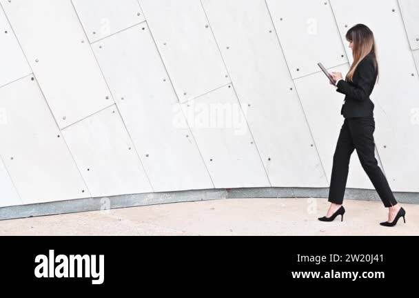 Business woman in corridor using tablet computer texting walking in ...