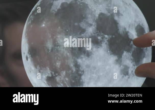 Reflection of a caucasian man looking at phases of the moon on a screen ...