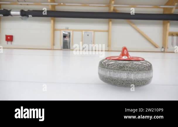 Curling game. Curler is sweeping the ice surface in the path of the ...