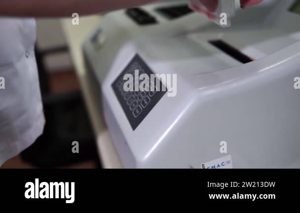 Female lab technician sets up a laboratory machine for blood analysis ...
