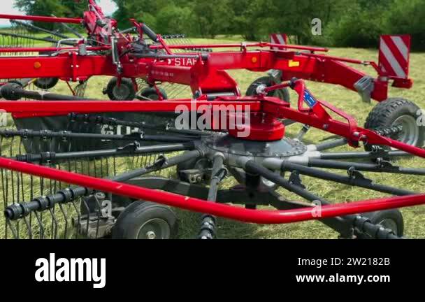 Red agricultural machinery is moving and it stay on the ground. It goes ...