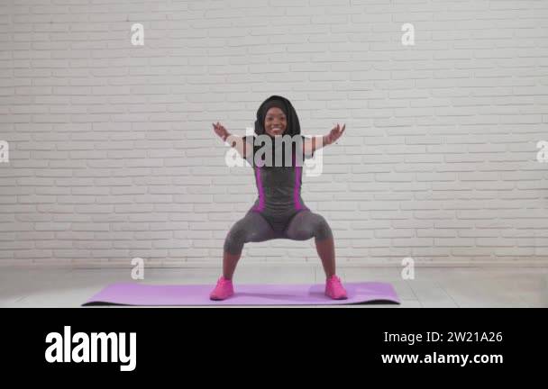 African woman doing squats on mat Stock Video Footage - Alamy