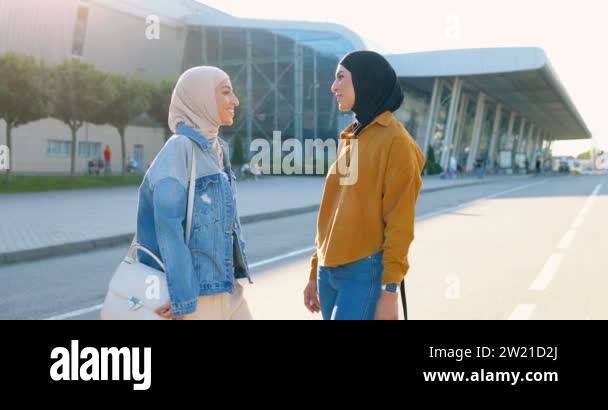 Two muslim young females, best friends in hijabs standing outdoor and ...