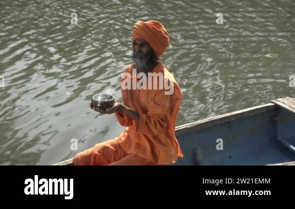 Indian monk floats in a boat with a holy cup, to an old temple, and ...