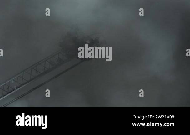 Firefighter battles fire below from firetruck's ladder but the smoke ...