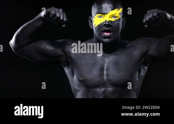 Man bodybuilder athlete with yellow color on face art and black body ...
