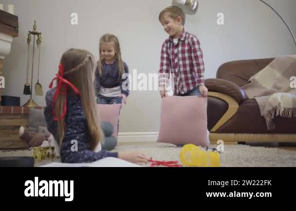 Little Caucasian boy and girl fighting elder sister with pillows ...