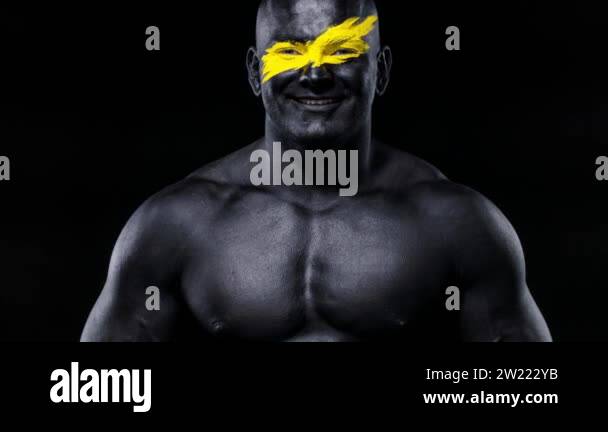 Man bodybuilder athlete with yellow color on face art and black body ...