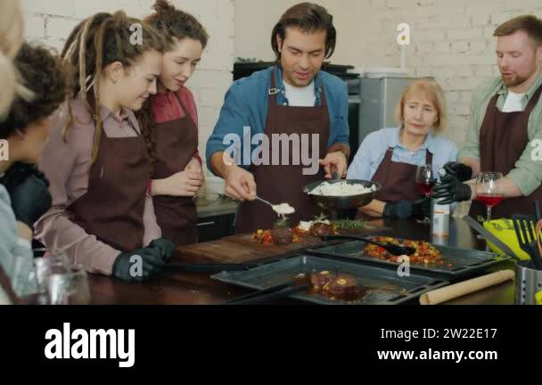 Joyful trainees of culinary class making dish with fire clapping hands ...