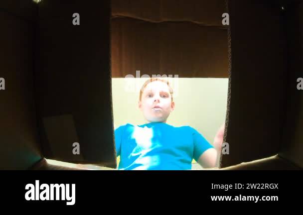 Amazed small red-haired boy with freckles opening cardboard box and ...