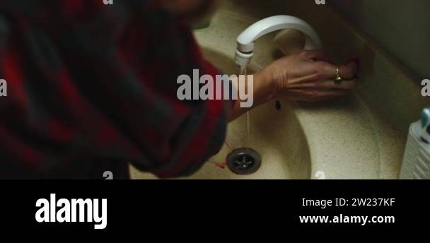 Woman washing bloody hands in the sink, close up. Horror murder concept ...