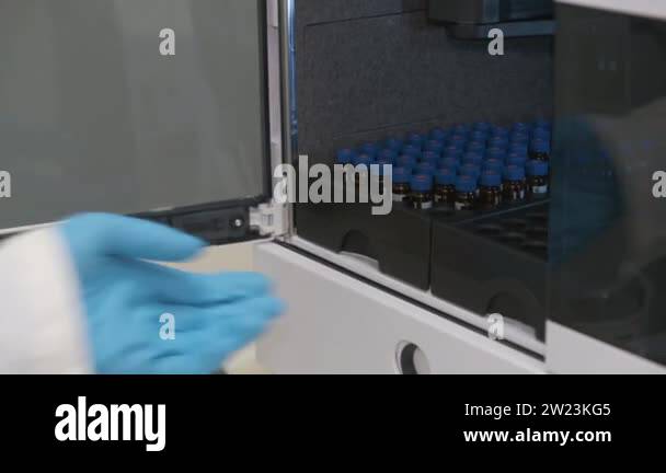 Analytical chemist puts a vials to auto sampler of HPLC system ...