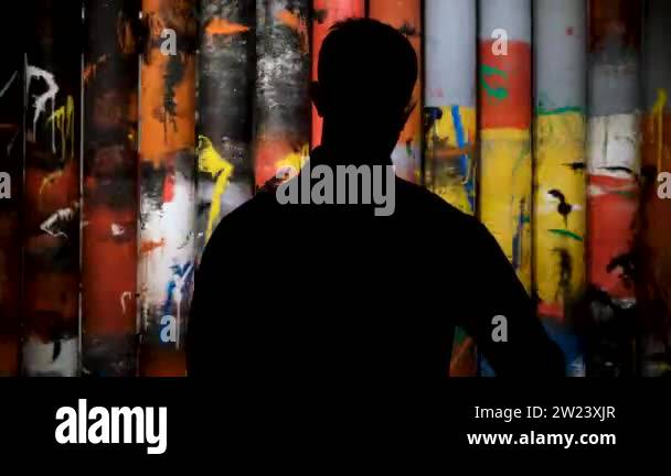 Rear view of a man silhouette standing in front of rotating columns ...
