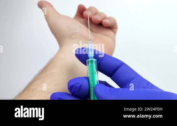 Macro video of a doctors hand with a syringe that draws blood from ...