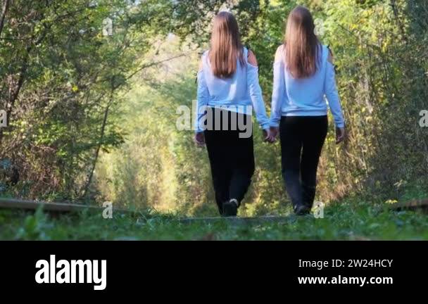 Twins Girls Holding Hands Walking Along Railroad Tracks. Back view ...