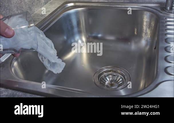 Person tips glass with plastic into the sink. Micro plastic in the sink ...