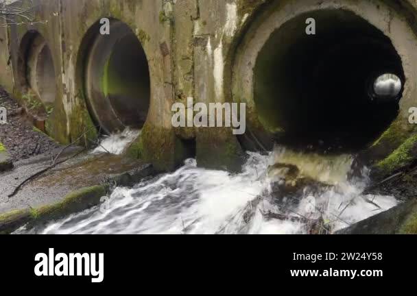 River dam made of pipes under a bridge in a forest road with running ...