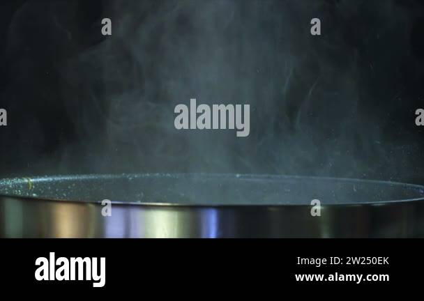 Splashes Oil, drops of water and smoke (vapor) come flying out of pan ...