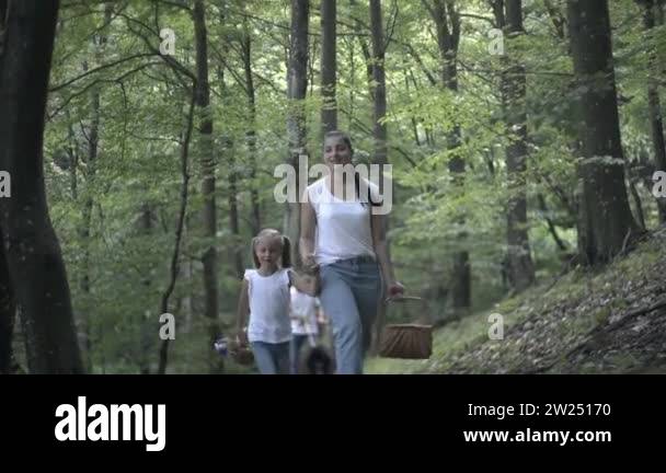 Family On Hiking Adventure Through Forest. Happy family of mother, father and daughters walking ...