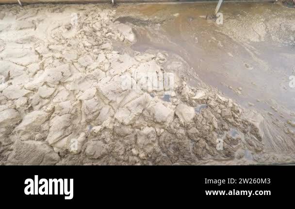 Sticky brown foam on slurry surface. Sewage treatment plant under city ...
