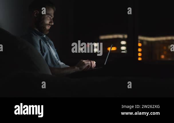 A side view of a handsome young man is using his laptop computer at ...