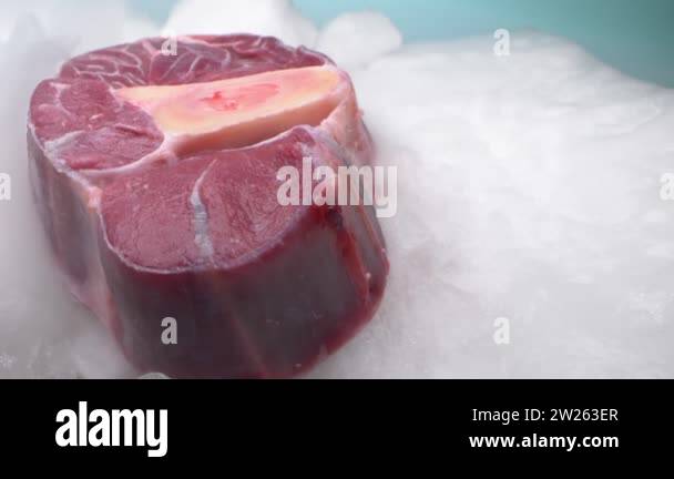 extreme close-up, detailed. piece of raw beef meat on the bone on ice ...