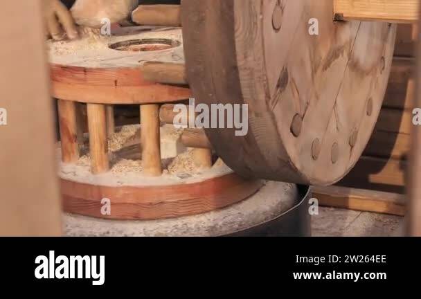 Miller puts grain in a rotating ancient quern stone. Mechanical manual ...